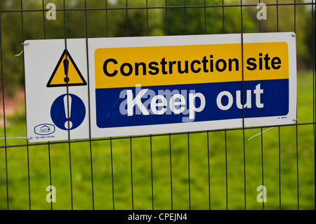 a keep out sign fixed to the security fence around a construction site ...