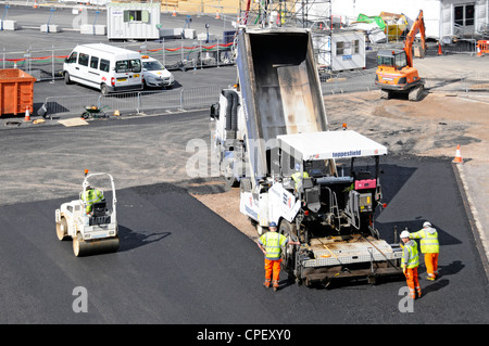 Tipper lorry and Tarmac laying machine with road roller and workmen ...