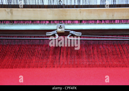 Old fashioned Welsh manual, hand operated weaving loom with red and ...