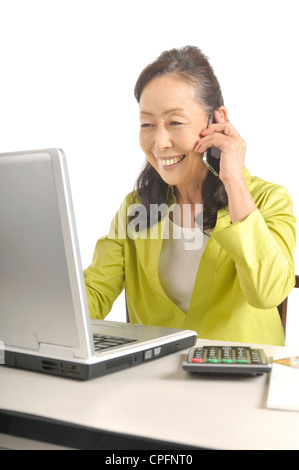 Asian woman using laptop and smartphone while working at modern home ...