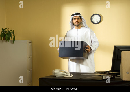 Arab man packing at office desk Stock Photo - Alamy