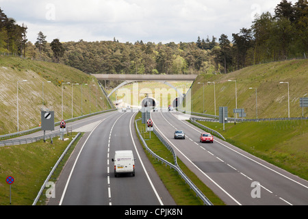 Entrance to a highway tunnel with two lanes, green traffic lights and ...