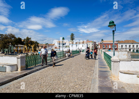 People crossing the Roman Bridge over the Gilao river, Tavira, Algarve ...
