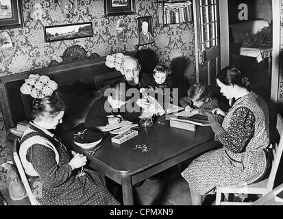 Portrait of lower middle class family sitting together on cot in the ...
