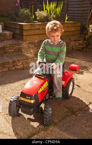 Boy riding toy tractor on field Stock Photo - Alamy