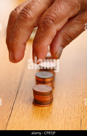 sterling 2p coins being sorted into small piles by an elderly person ...