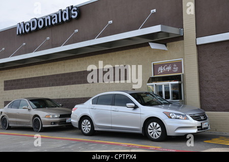 Cars use a drive through window to order and pick up fast food at a ...