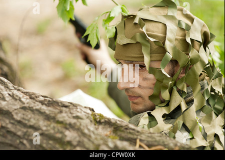 Camouflaged sniper in the forest in ambush. Military man aiming a gun, a rifle at the enemy in ...