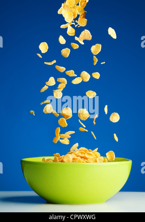 Tasty corn flakes falling into bowl on light blue background Stock ...