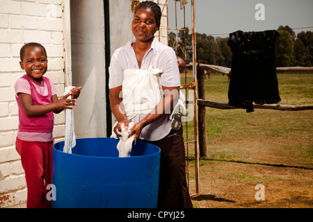 African girls washing laundry by hand in brightly coloured buckets ...