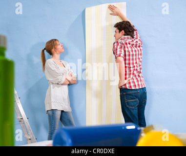 Young couple applying wallpaper to a wall Stock Photo - Alamy