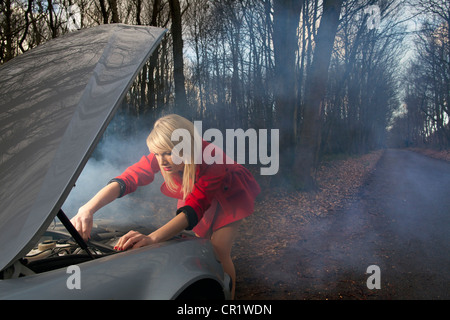 Young woman looking under the hood bonnet of a car appearing confused Stock Photo: 21259035 - Alamy