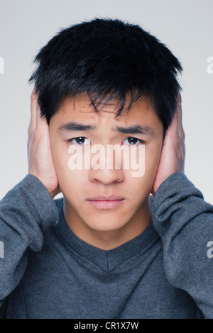 Man blocking his ears and looking at camera Stock Photo - Alamy