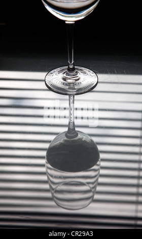 A wine glass reflected in a glass cutting board in a domestic kitchen ...