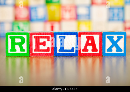 The word 'relax' spelled out in colourful plastic letters, on green ...