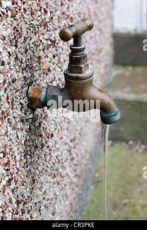 Close-up of a dripping faucet wasting water, highlighting the ...