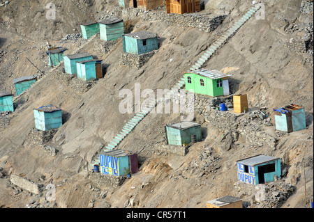 Brightly painted wooden houses built on sandy slopes in the dry desert ...