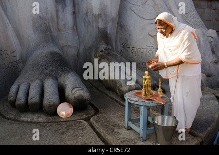 A Jain pilgrim is pouring water over the feet of the statue of Lord ...