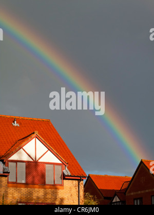 Brightly coloured rainbow with stormy sky over rooftops in Bristol ...