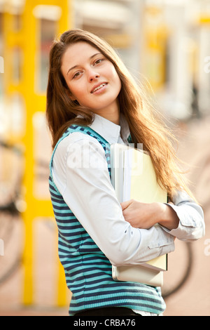 Student with a laptop and a workbook under her arm, smiling Stock Photo ...