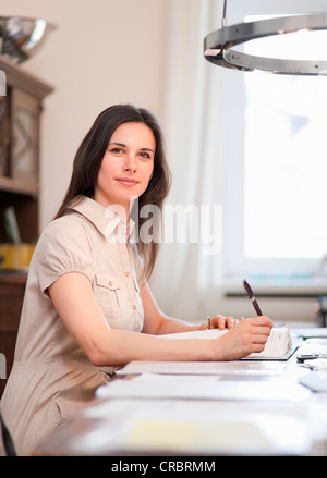 women seated at home office writing notes journal planning tasks with ...