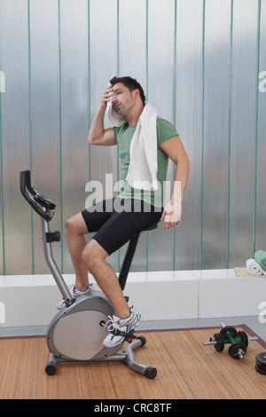 Young adult man wiping sweat from his forehead, catching his breath and ...