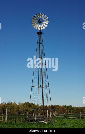 A Windmill for pumping water from wind power on grass fields under blue ...