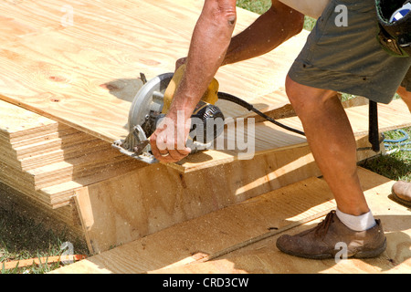 Worker uses circular saw to cut wood on construction project outside ...