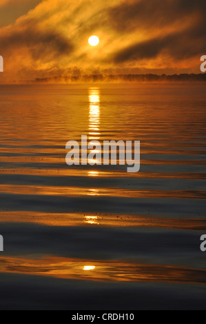 Clouds lit by morning light reflecting in a pond, surrounded by distant ...