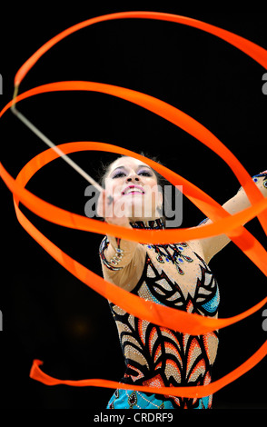 Young gymnast woman doing movements with pink ribbon against white ...