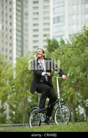 Smiling businessman riding a bicycle Stock Photo - Alamy