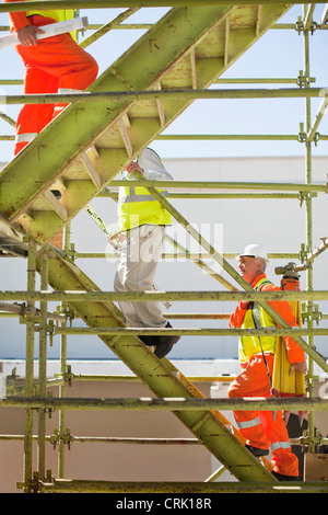 builder climbing on scaffolding at construction site and looking away ...