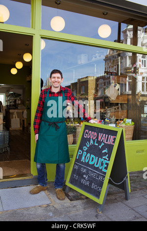 Smiling grocer standing outside store Stock Photo - Alamy