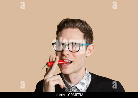 Mid adult man smoking red chili pepper over colored background Stock ...