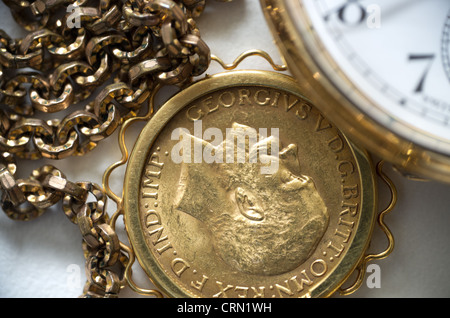 A gold pocket watch by Record with Arabic numerals and intricate gold ...