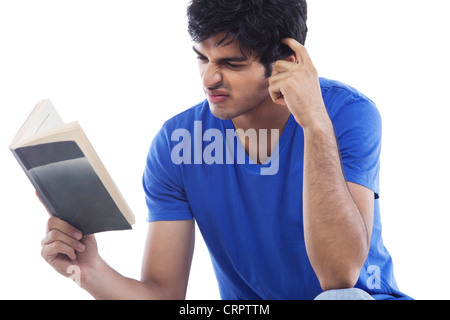 Picture of confused young man sitting near laptop and holding head with ...
