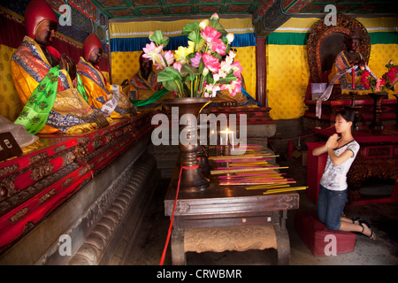 People praying inside one of the main buildings at Yonghe Temple ...