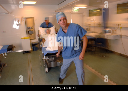 Two hospital porters wheeling patient on trolley bed to operating ...