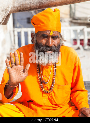 Sadhu dressed in orange robes, with a long white beard, sitting by the ...
