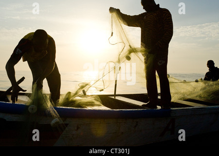 A group of fishermen is pulling a fishing net out of the sea on the ...