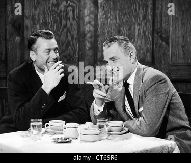 Businessmen smoking cigarettes and smiling at dinner Stock Photo - Alamy