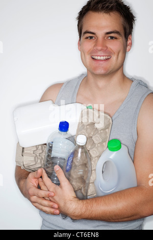 Young handsome man holding plastic water bottle over yellow isolated ...