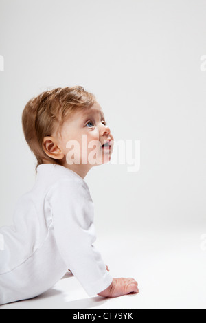 Young cute caucasian girl crawling forward on her stomach toward the ...