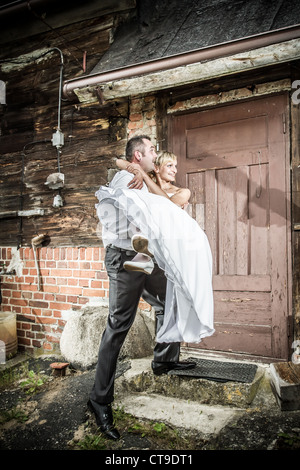 Young happy couple in the village among the haystacks. Guy is playing ...