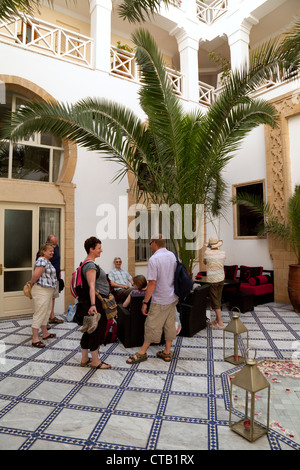 Guests arriving at hotel reception in lobby, entering lounge area and ...