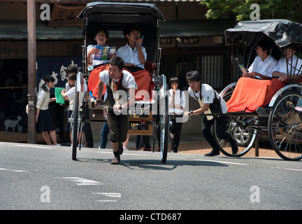 Tourists riding in rickshaws in Nara, Japan. The rickshaw-pullers wear ...