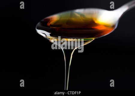 Honey trickle dropping of a full spoon Stock Photo - Alamy