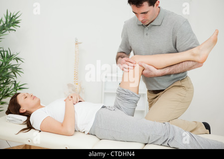 Serious osteopath bending the leg of a patient Stock Photo - Alamy