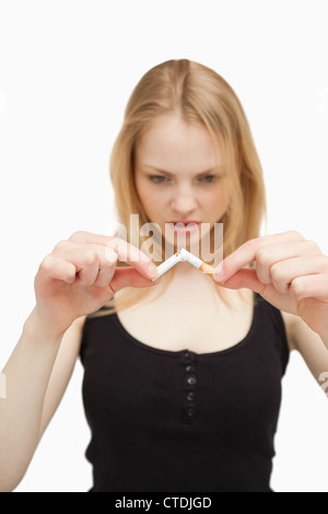 Blonde-haired woman breaking a cigarette against white background Stock ...