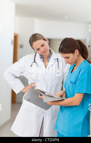 A doctor with a stethoscope is reading files in the face of a patient ...